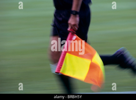 Linesman running whilst holding a flag Stock Photo - Alamy