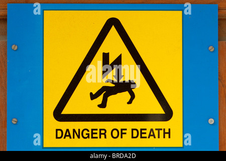 A triangular 'Danger of Death' warning sign on a wooden pole carrying ...