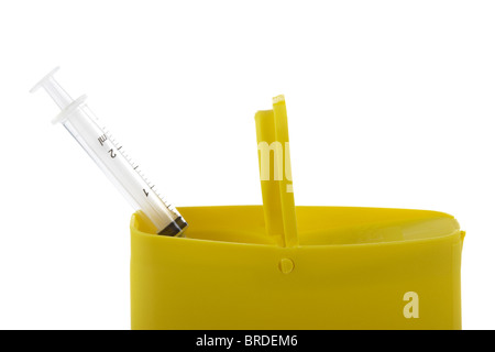 disposing of a hypodermic syringe and needle in a yellow plastic sharps ...