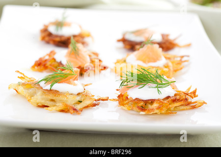 Bite sized potato rosti appetizer topped with fresh sour cream, smoked ...