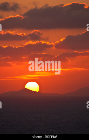 Sun setting behind a distant hill, flaming red Stock Photo - Alamy