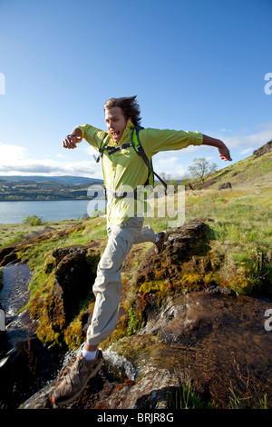 Man jumping across stream Stock Photo - Alamy