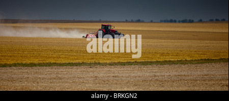 Caption Red tractor rotovating a field of straw stubble in France Stock ...