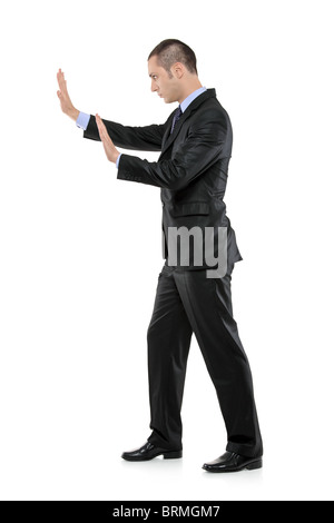 Full length of businessman pushing something against white background ...