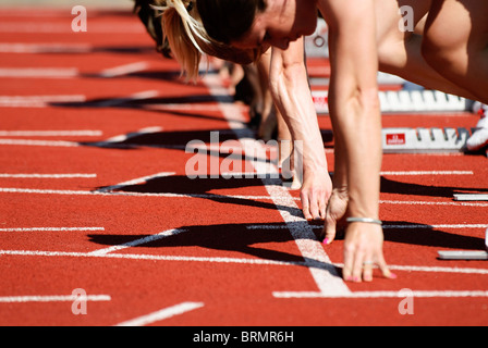 female runners anticipating start at starting line of track and field ...