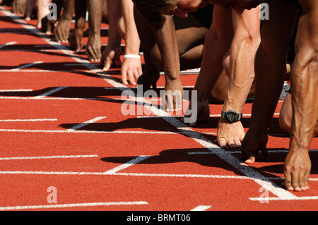 male sprinters line up their hands on the starting line at track and ...