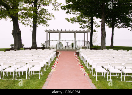 Outdoor wedding ceremony setup with white chairs and floral aisle Stock ...