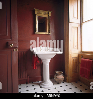 White pedestal basin below window in black+white attic bathroom with ...