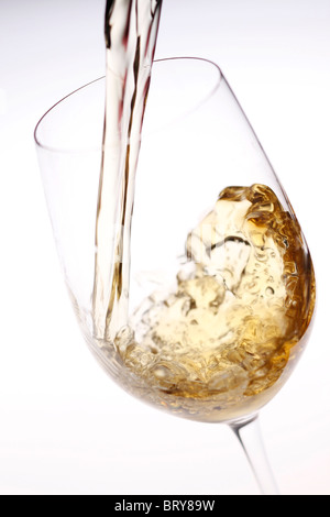 White wine being poured into a wineglass, isolated on white background ...