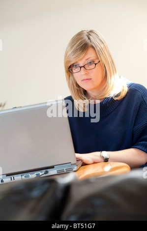 young female shopping online at home sitting besides row of shopping ...
