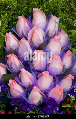 A closeup shot of rose-scented square soap on a wooden stand surrounded ...