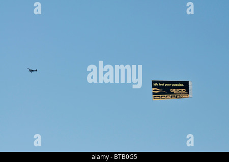 Small airplane towing an advertising banner for GEICO Powersports ...
