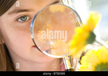 Girl observing plants through a magnifying glass with a smile in ...