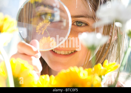 Girl observing plants through a magnifying glass with a smile in ...