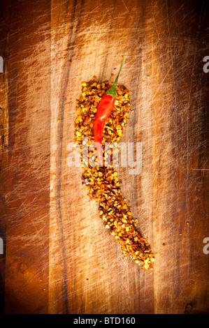 Red hot chilli concept - chilli sits atop chilli seeds shaped like a ...