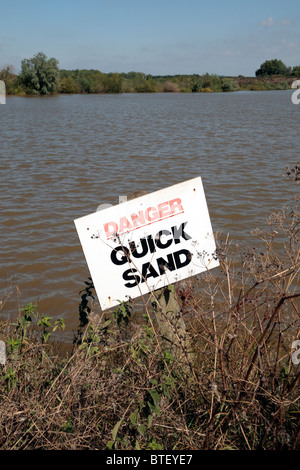 A 'Quicksand' warning sign at the edge of a lake in England, UK Stock ...