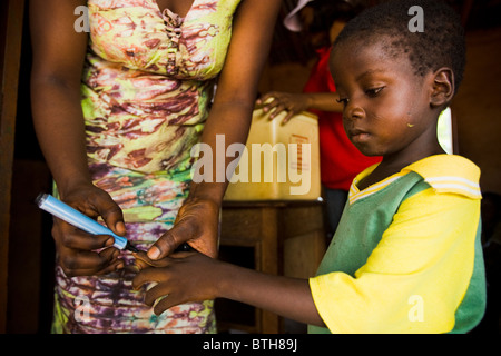 A health worker marks the finger of a child with ink during a national ...