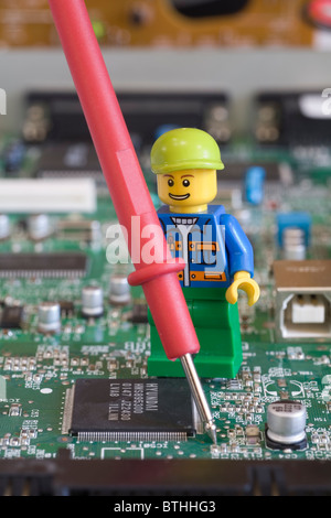 Lego engineer on an electronic circuit board holding an electronic ...