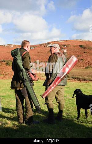 Gamekeeper game shooting with gun dog in field, black & white ...