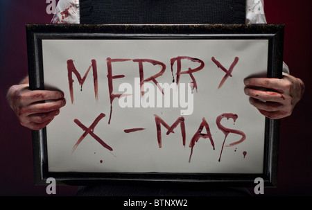 Horror Christmas Elf holding a sign written with blood Stock Photo - Alamy