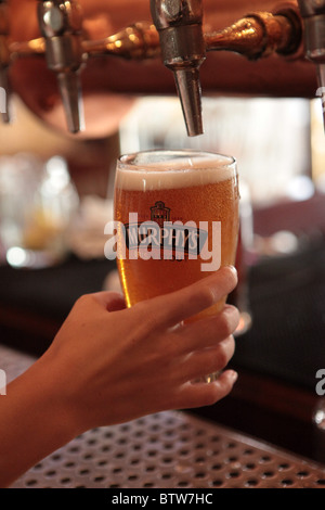 Interior of an Irish style pub draught beer taps. Barmaid pouring a ...