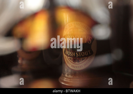 Interior of an Irish style pub draught beer taps. Barmaid pouring a ...
