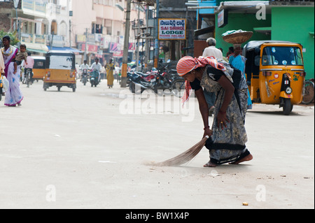female street cleaner brushing streets with broom early morning in lan ...