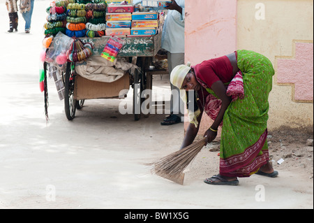 female street cleaner brushing streets with broom early morning in lan ...