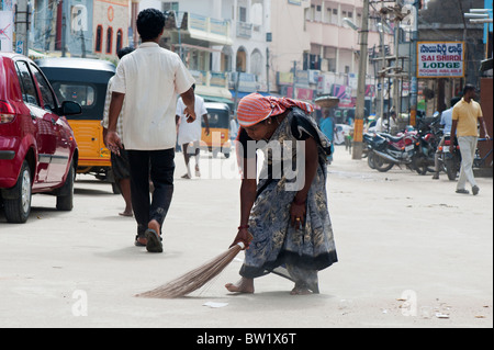 female street cleaner brushing streets with broom early morning in lan ...