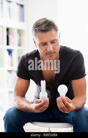Guy looking at light bulb sitting on grass Stock Photo - Alamy