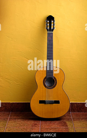 Guitar leaned to a yellow wall Stock Photo - Alamy