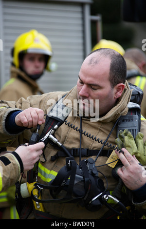A firefighter putting on a breathing apparatus gear for a hazmat suit ...