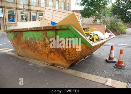 Overloaded skip of builders waste and rubble outside a semi-detached ...