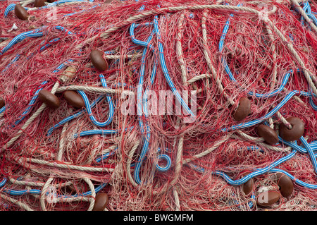 Heap of red fishing nets with ropes and floats Stock Photo - Alamy