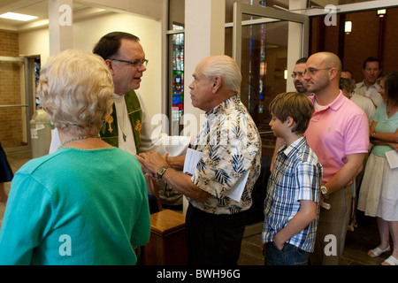 Anglo male pastor shakes hands as congregation lines up to leave the ...