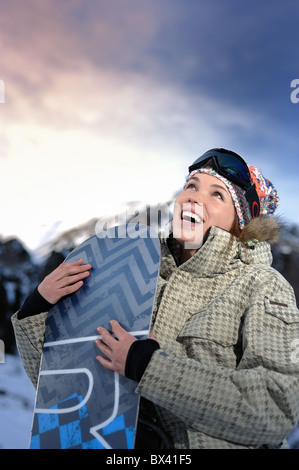 Pretty girl with snowboard looking up Stock Photo - Alamy