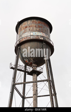 An old rusty water tank covered with graffiti sits in the setting sun ...