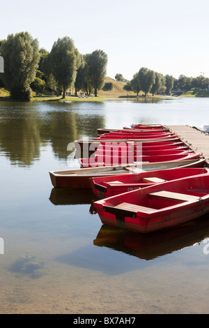 A tranquil scene of a small jetty on a pond with reeds and a field ...
