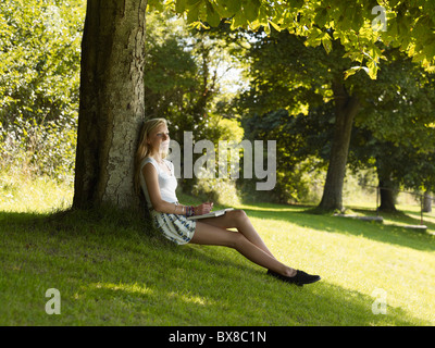 Teenage girl sitting under a tree Stock Photo: 76533385 - Alamy