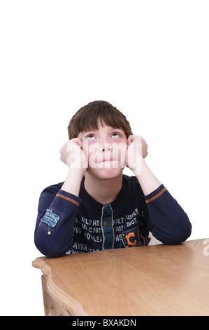 The white boy behind a table looks upwards thoughtfully Stock Photo - Alamy