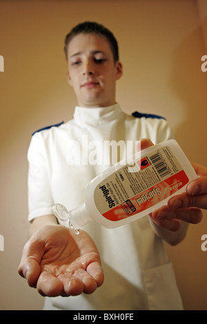 A male nurse demonstrates the use of alcohol based hand gel for ...