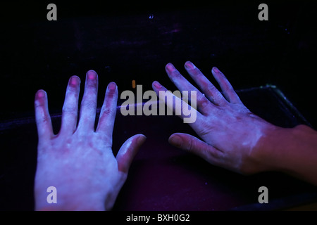 Hands placed under a UV light source indicate how effective normal hand ...