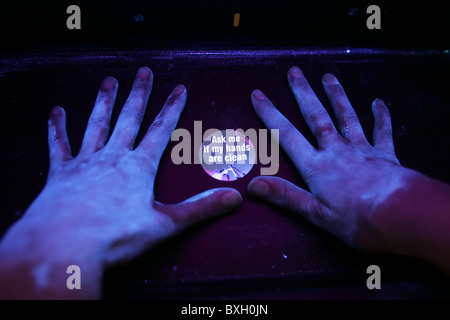 Hands placed under a UV light source indicate how effective normal hand ...