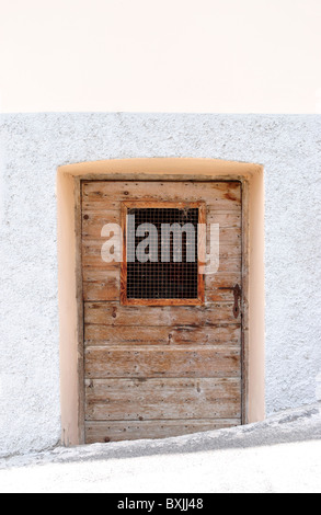 old wooden door below street level with a small window Stock Photo - Alamy