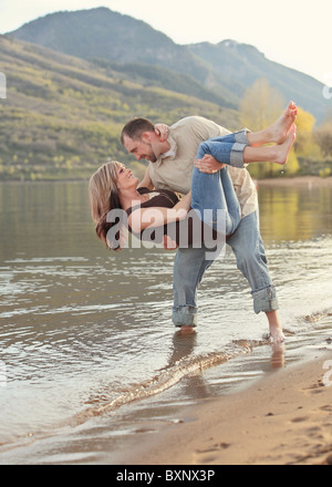 Playful young happy couple playing video games on sofa in modern white ...