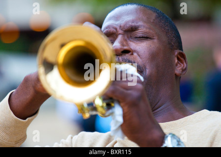 Street musician playing the trumpet in the shadows of the City Hall ...