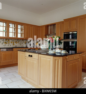 Pale wood fitted units with granite worktops in modern kitchen with ...