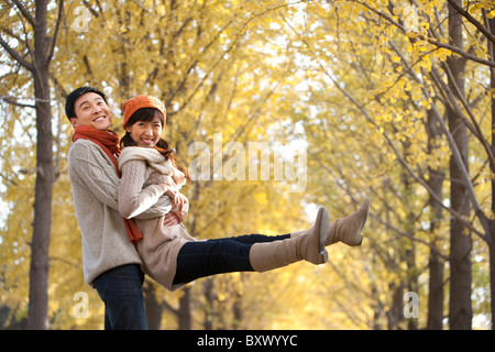 playful young man picking up his girlfriend by the lake in fall Stock ...
