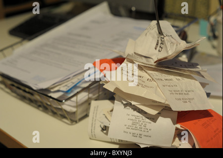 Receipts and bills on a spike in an office on a desk ready to be dealt ...