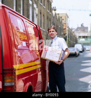 Royal Mail postman carrying packages from his van across Pall Mall in ...